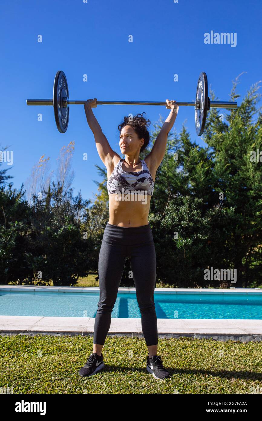 Eine Frau mittleren Alters trainiert in seinem Garten Crossfit und ...