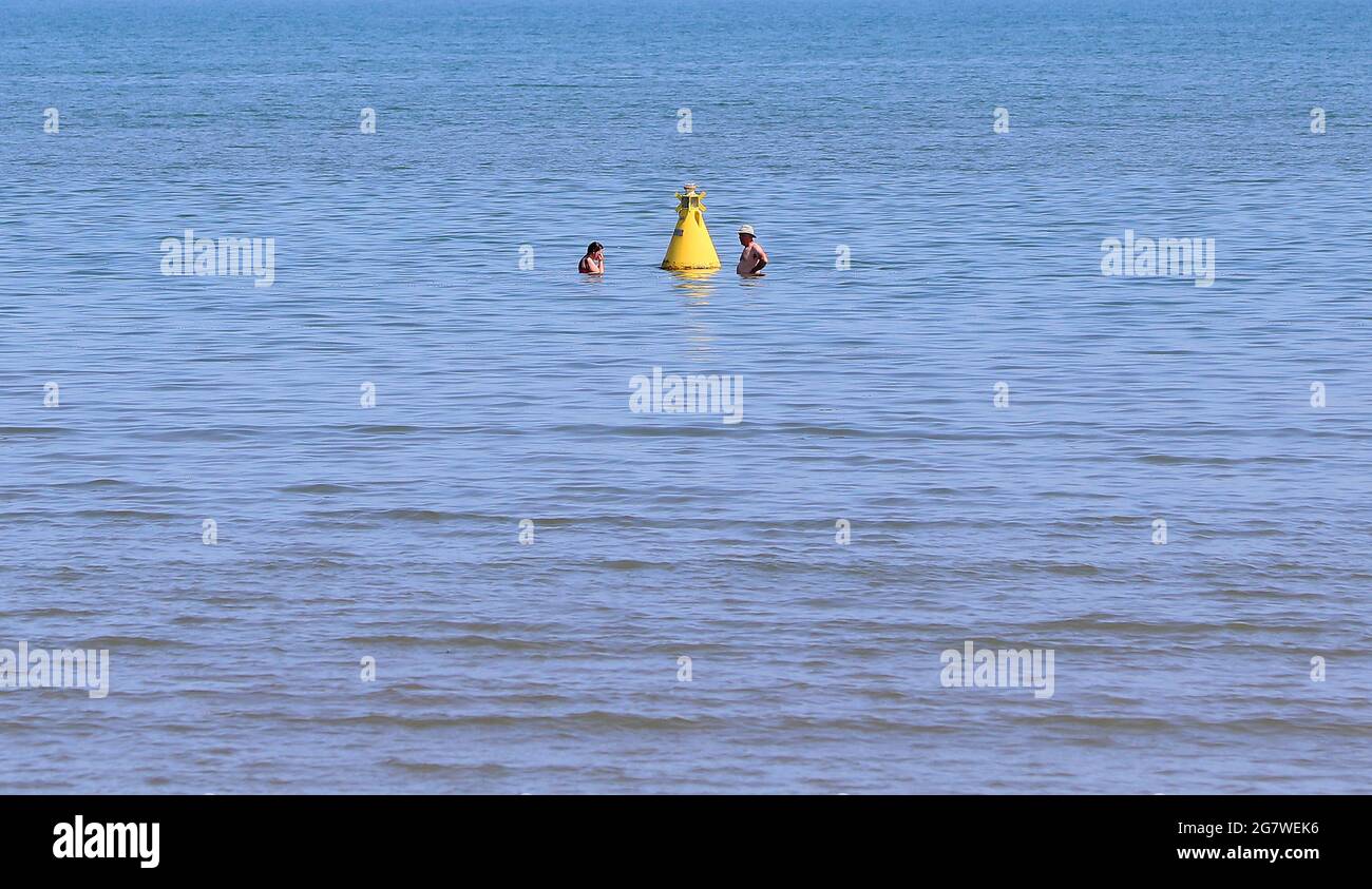 An einem heißen Sommertag halten die Menschen an, um an einer Boje zu ...