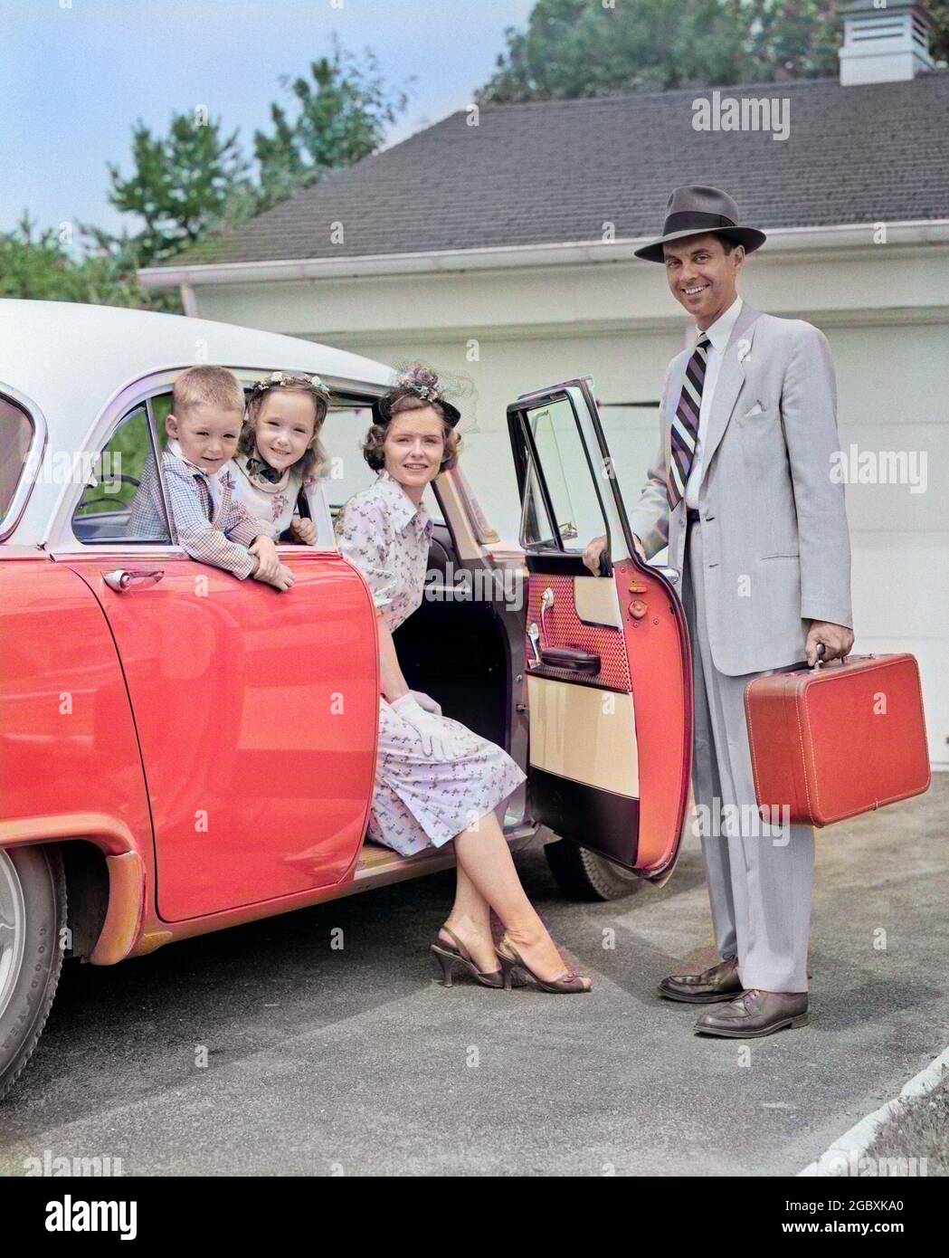 LÄCHELNDER VATER AUS DEN 1950ER JAHREN, DER KOFFER HIELT, WÄHREND ER ...