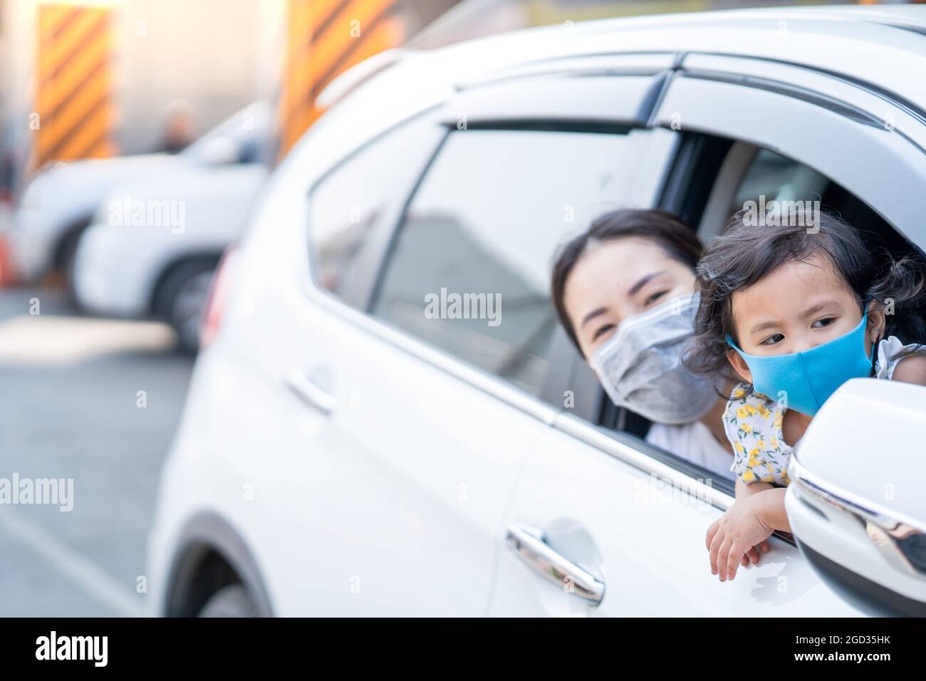 Die junge Mutter und ihr Kind aus Thailand blicken in Masken aus den ...