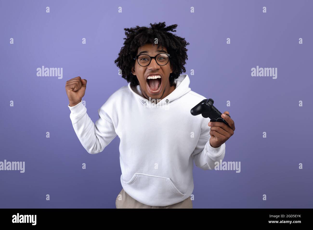 Triumphender schwarzer Teenager-Kerl mit Joystick, der in Aufregung ...