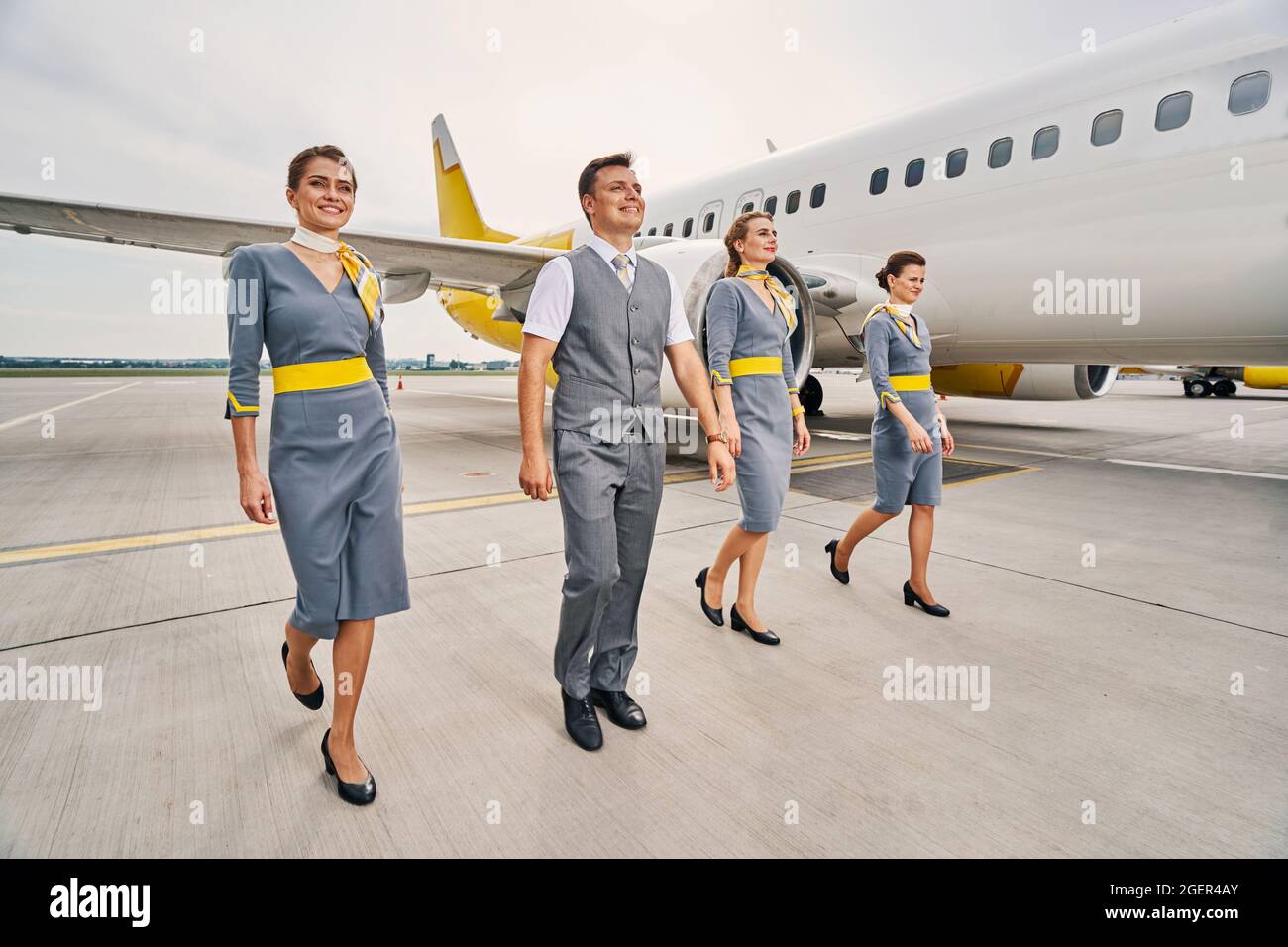 Fröhliche Flugbegleiterin und seine Kolleginnen, die vorangehen ...