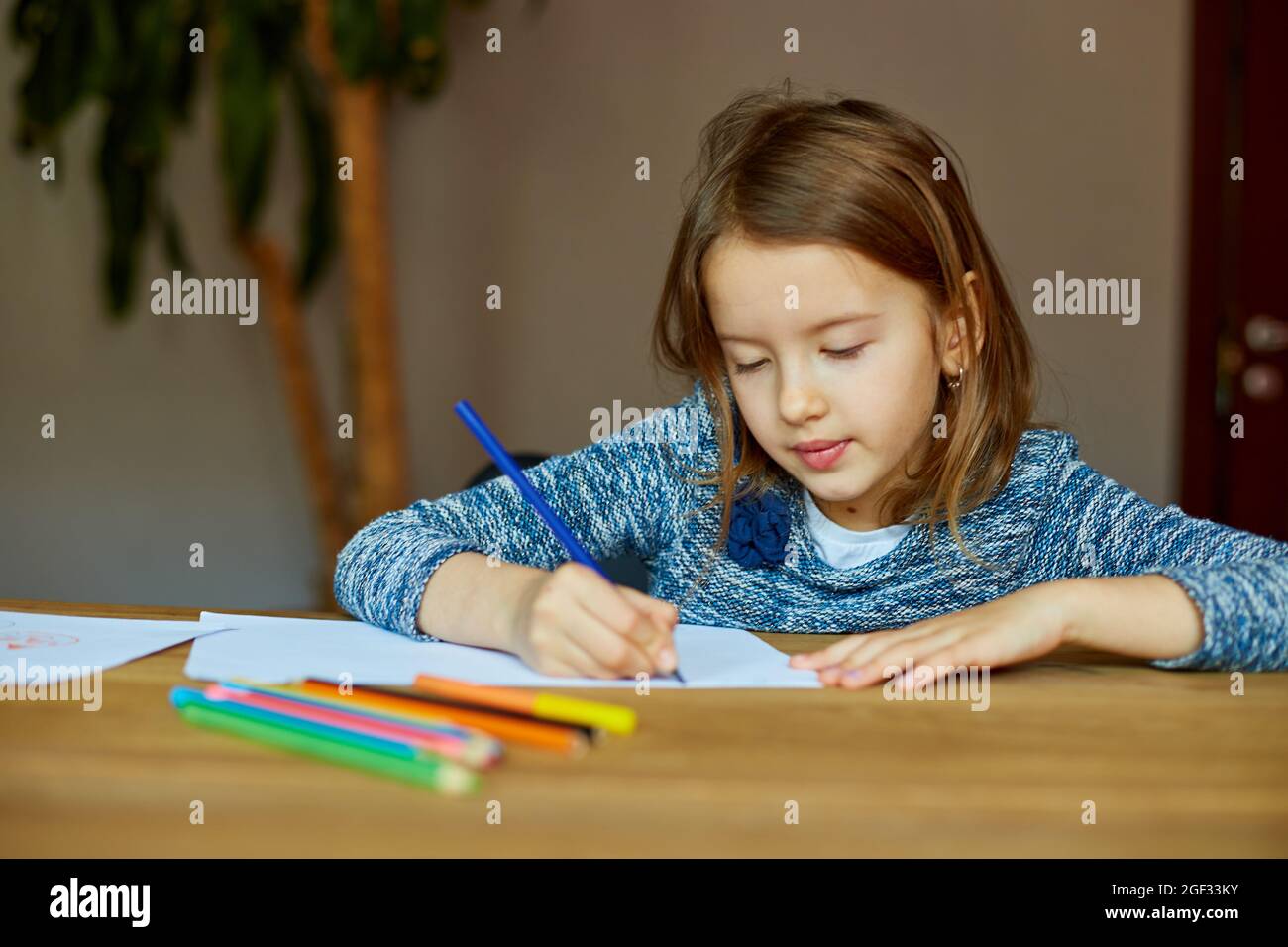 Schulmädchen zeichnen und schreiben ein Bild mit Buntstiften, mit Buntstiften am Tisch zu Hause ...