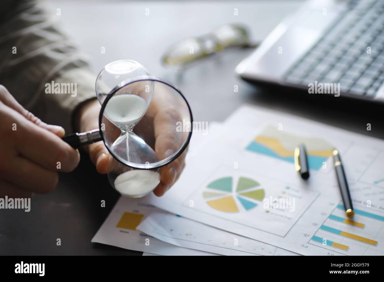 Arbeitszeit symbolisiert eine Sanduhr. Schreibtisch mit ...