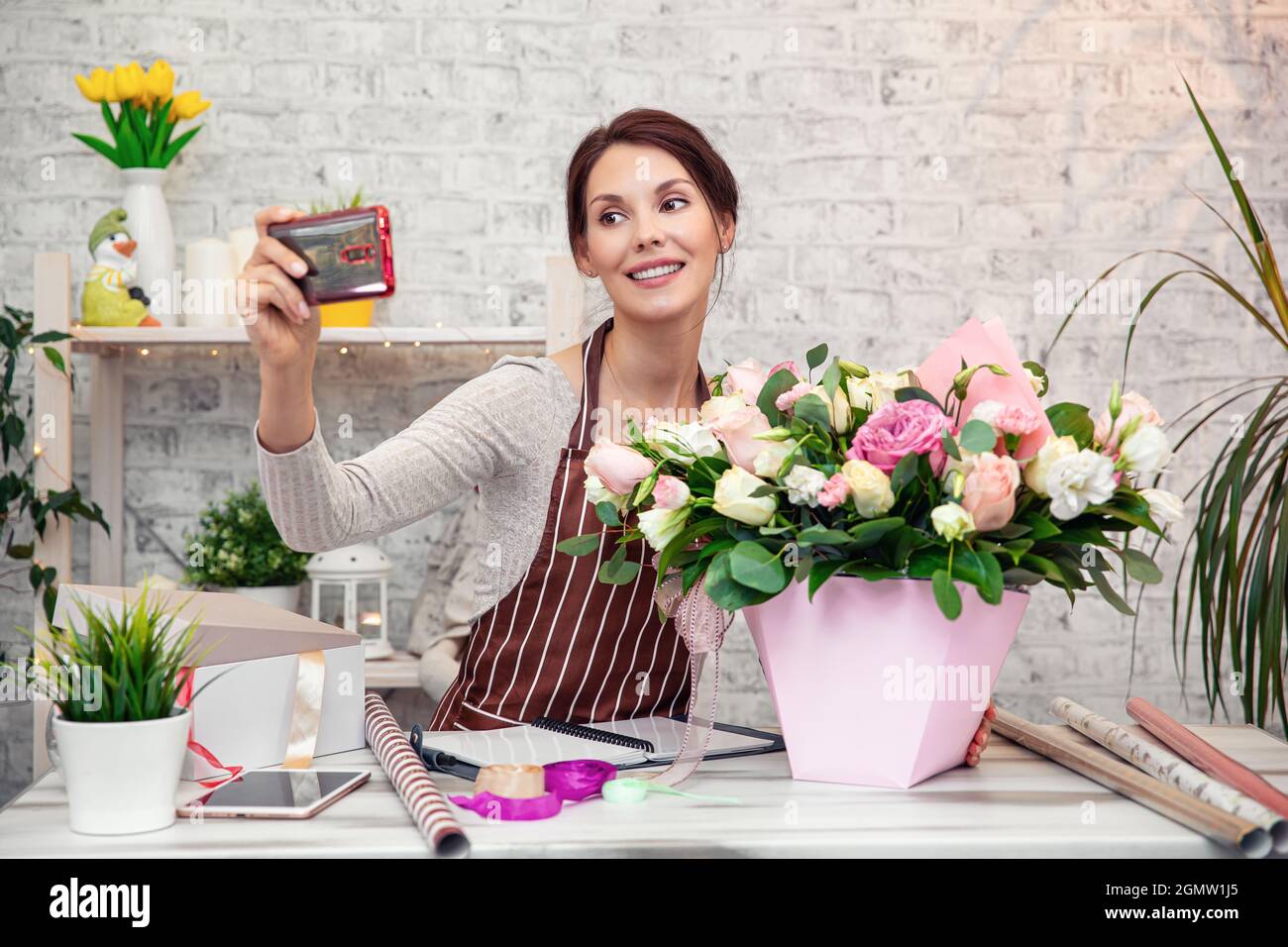 Junge Frau Floristin bei der Arbeit. Geschäftsfrau macht ein Selfie mit ...