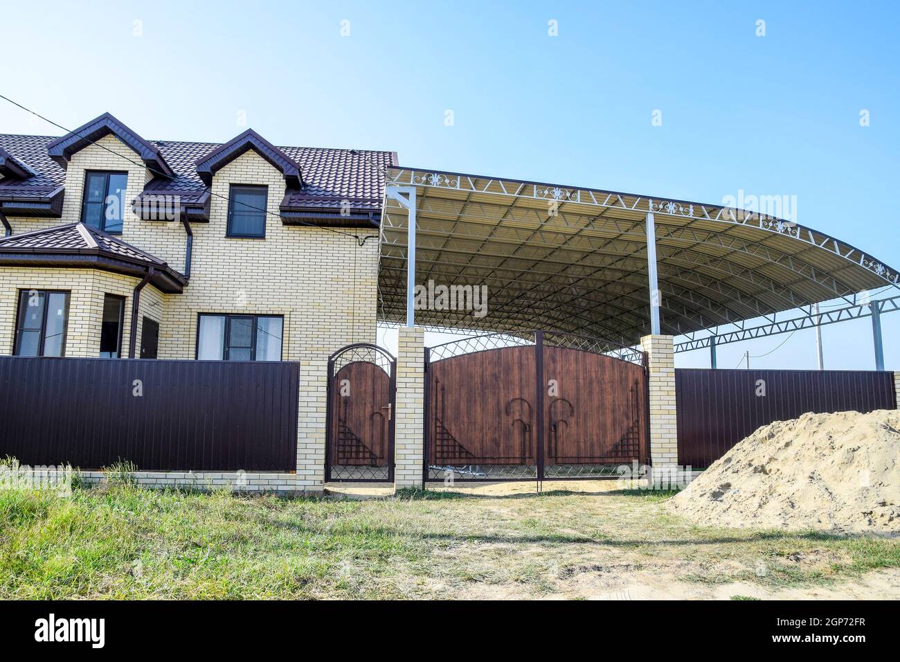 Brick House mit einem Zaun und Tore. Eine große Markise mit Stahlrahmen ...