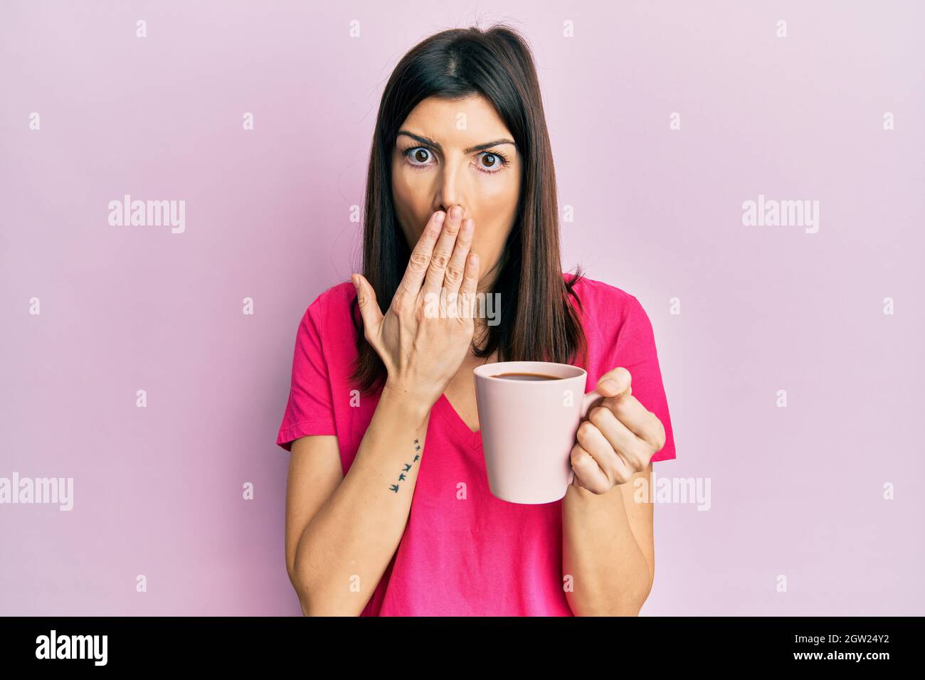 Junge hispanische Frau trinkt eine Tasse Kaffee mit ärgerem Gesicht ... Junge hispanische Frau trinkt eine Tasse Kaffee mit ärgerem Gesicht ...