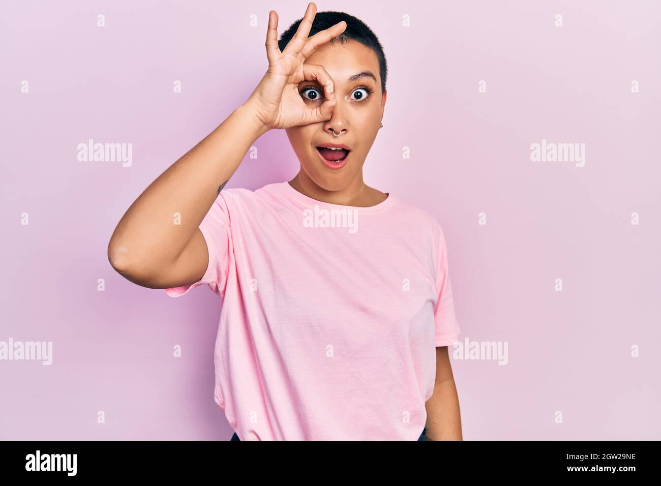 Schöne hispanische Frau mit kurzen Haaren tragen lässige rosa T-Shirt ...