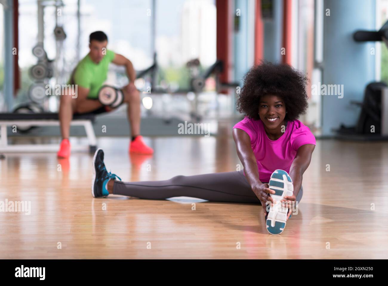 glückliche junge afroamerikanische Frau in einem Fitnessstudio, dehnen ... glückliche junge afroamerikanische Frau in einem Fitnessstudio, dehnen ...