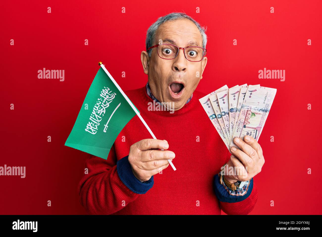 Hübscher älterer Mann mit grauem Haar, der die Saudi-arabische Flagge ...