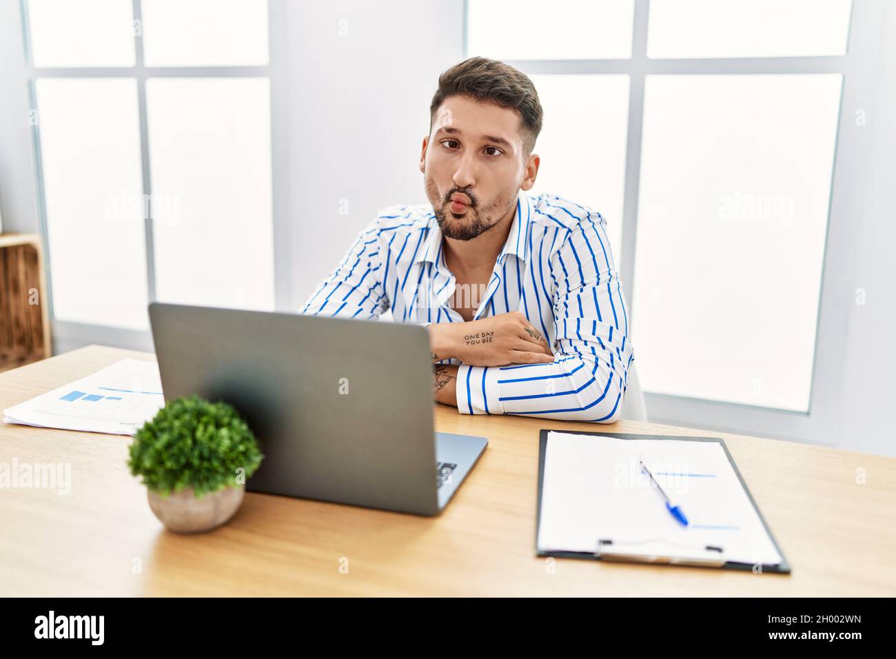 Junger, hübscher Mann mit Bart, der im Büro mit einem Computer-Laptop ... Junger, hübscher Mann mit Bart, der im Büro mit einem Computer-Laptop ...