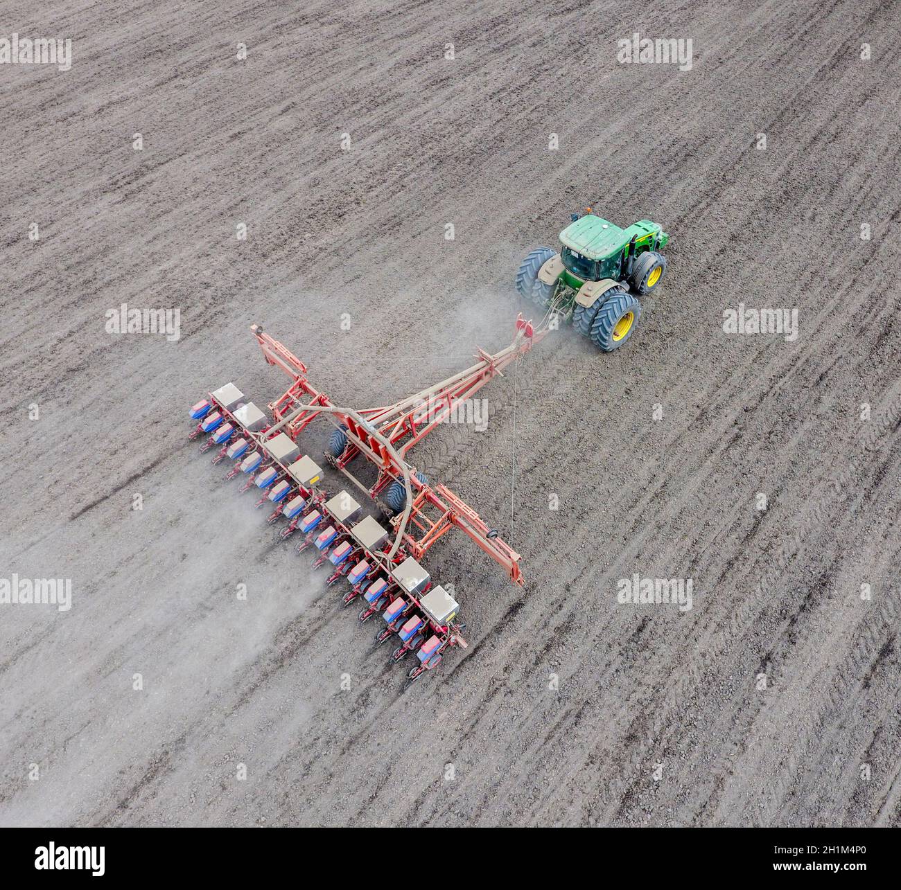 Aussaat von Mais. Traktor mit einer Sämaschine auf dem Feld. Mit Hilfe ...