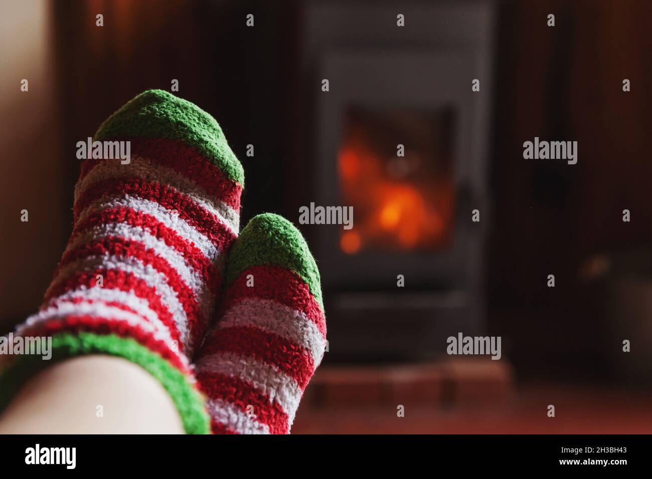Füße Beine im Winter Kleidung Wolle Socken am Kamin Hintergrund. Frau ...