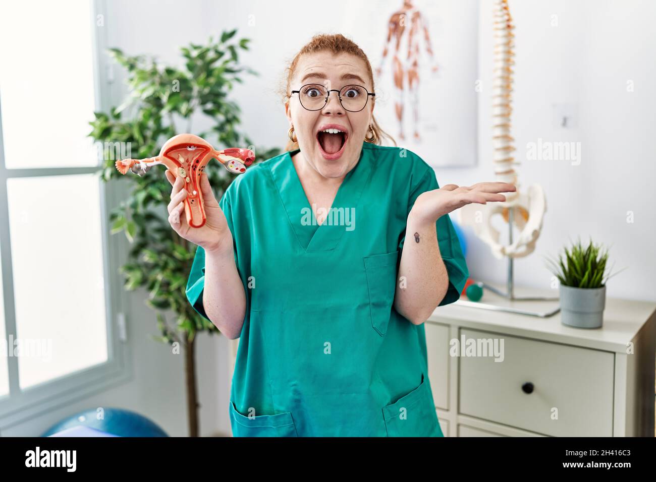Junge Rotschopf-Ärztin mit anatomischem Modell des weiblichen ...