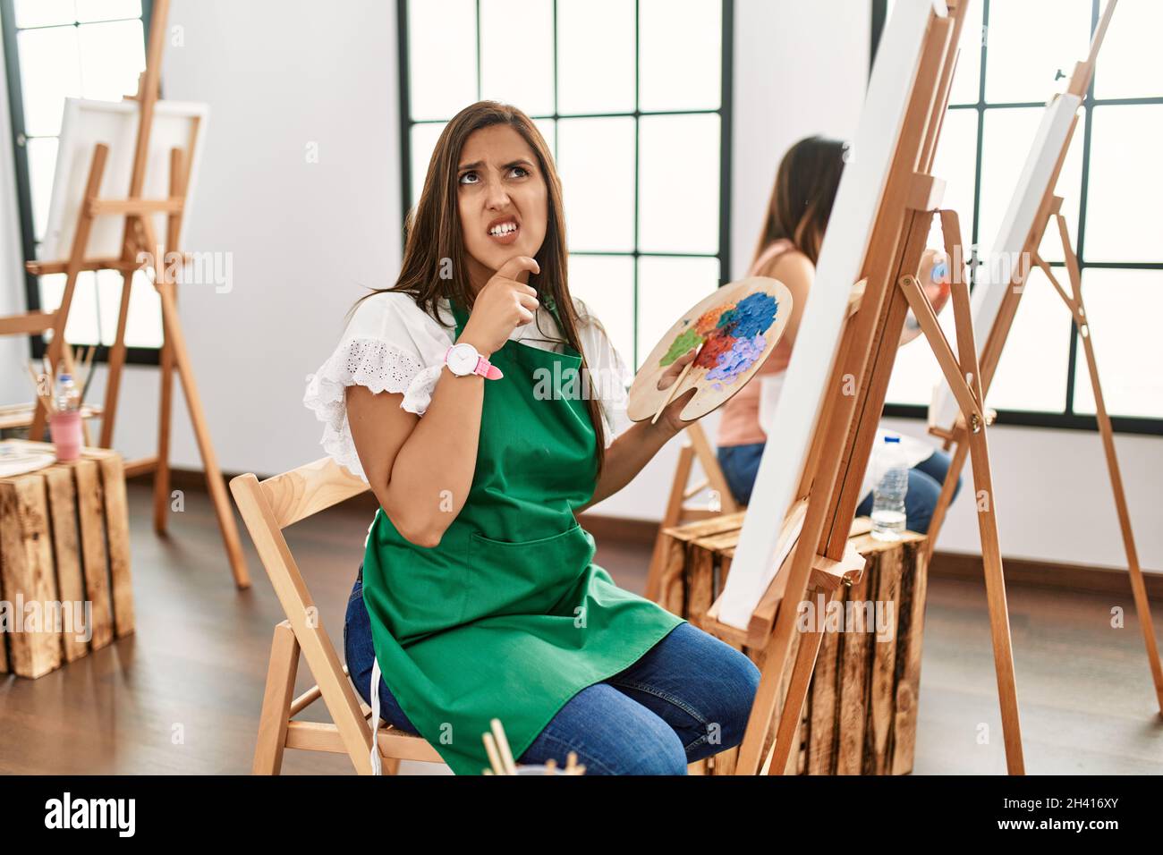 Junge hispanische Künstlerinnen malen auf Leinwand im Kunststudio und ... Junge hispanische Künstlerinnen malen auf Leinwand im Kunststudio und ...