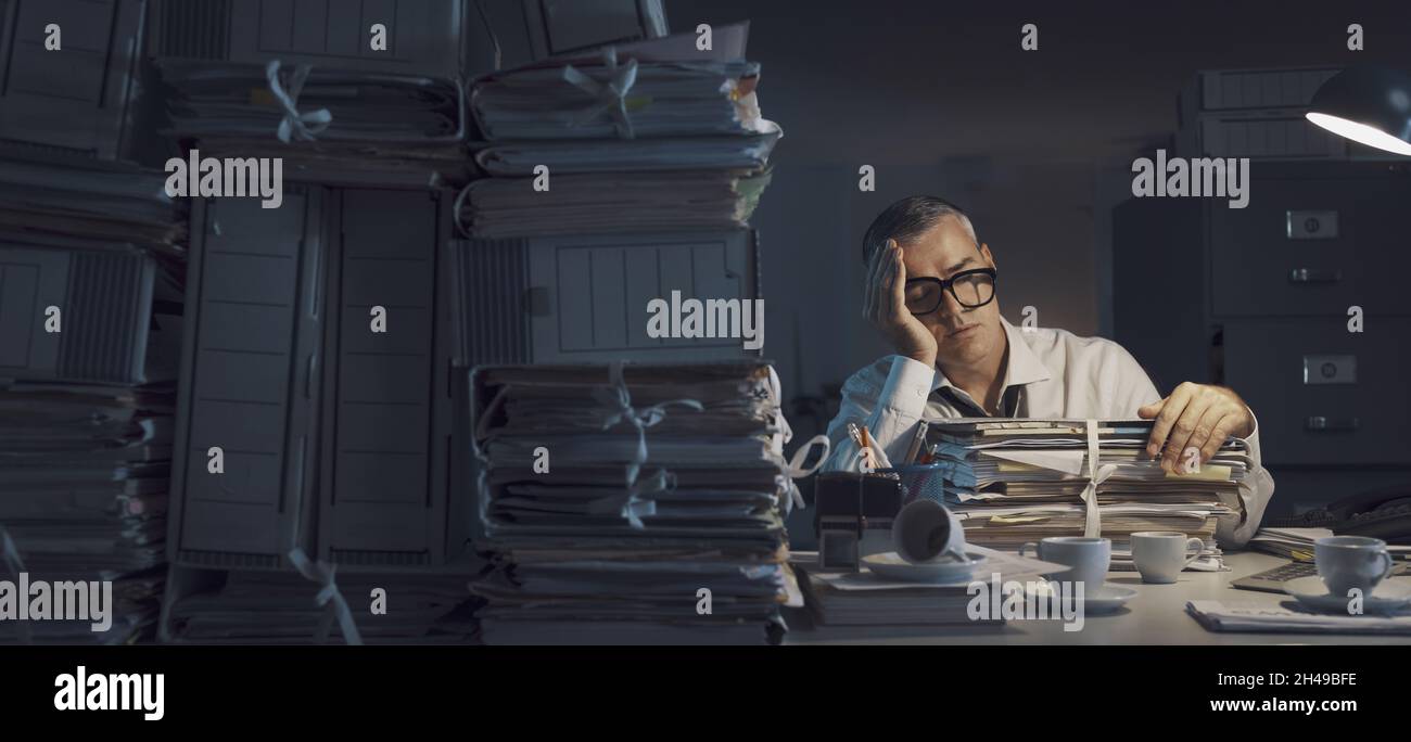 Erschöpfter Geschäftsmann, der spät in der Nacht an seinem Schreibtisch ...