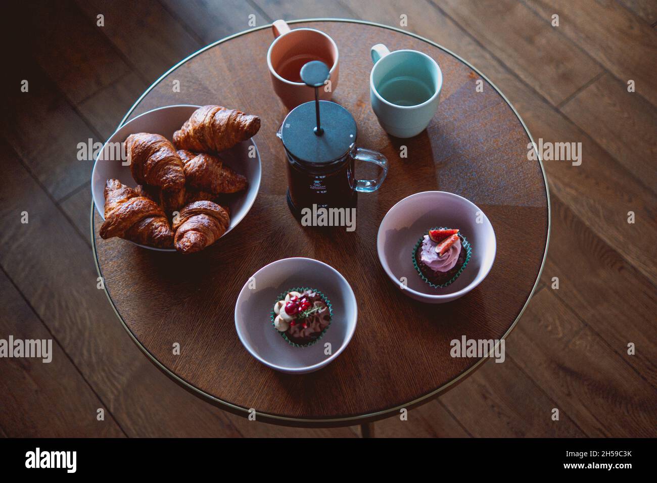Nahaufnahme von Tassen Kaffee mit Cupcakes und Croissant-Brot in weißen ...