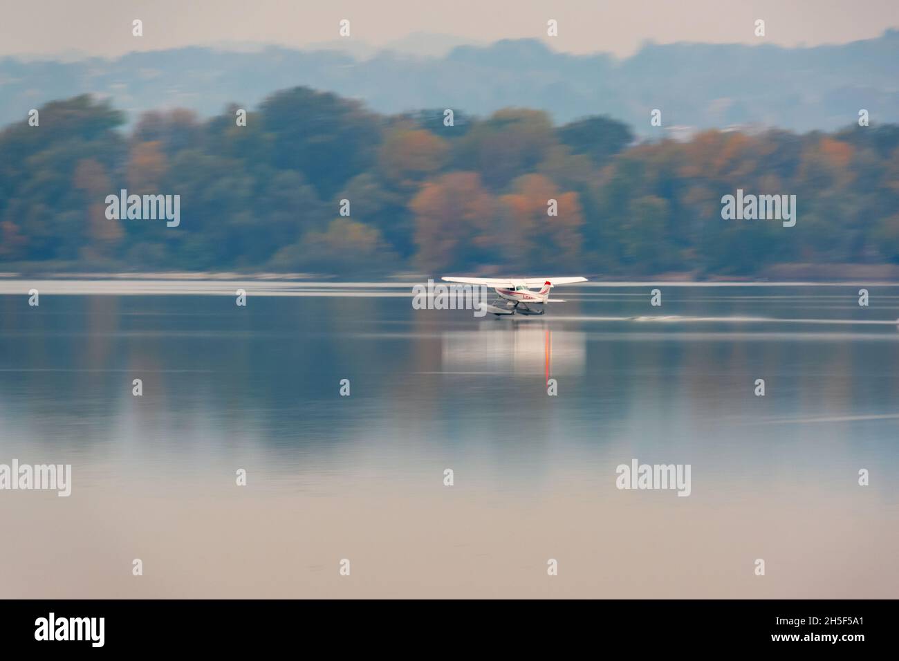 Ein kleines weißes Wasserflugzeug fliegt an einem trüben Tag von einem ...