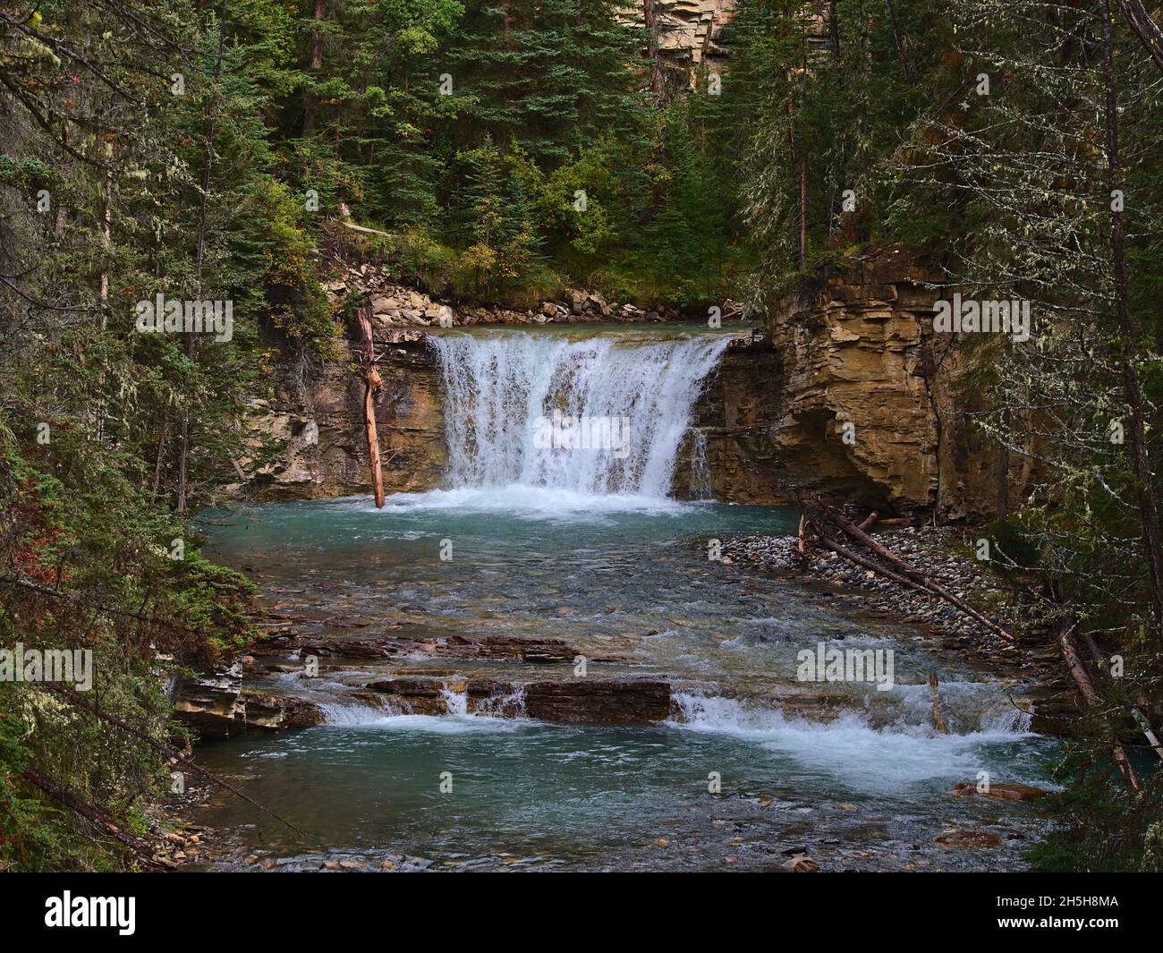 Fluss mit klarem Wasser und kleinem Wasserfall im Johnston Canyon ...