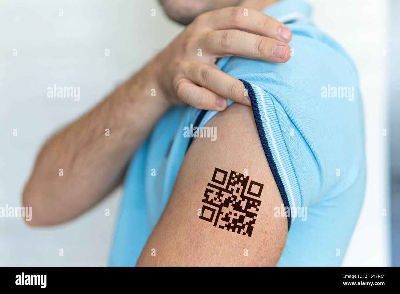 Der Mann zeigt seine Schulter mit einem qr-Code, einer Bestätigung der ...