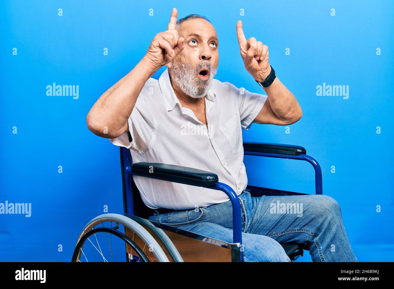 Schöner älterer Mann mit Bart auf dem Rollstuhl sitzend, erstaunt und ...