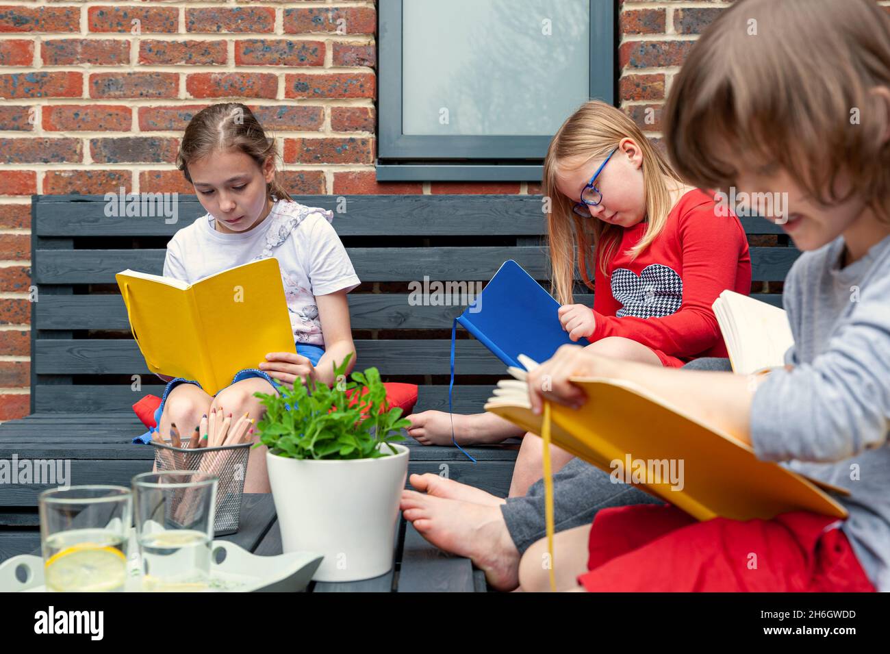 Eine Gruppe von Freunden aus der Schule sitzt zusammen im Garten und ...