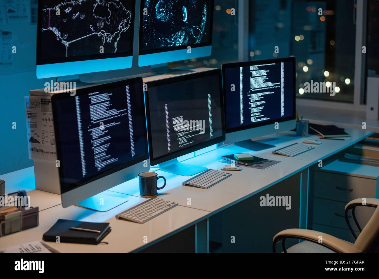 Arbeitsplatz moderner IT-Ingenieure mit drei Computern, die auf dem ...