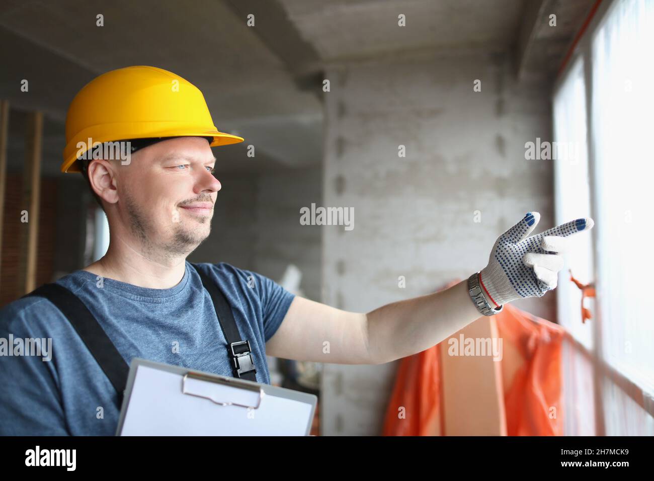 Der Vorarbeiter hält den Bauplan und zeigt nach draußen, um den ...