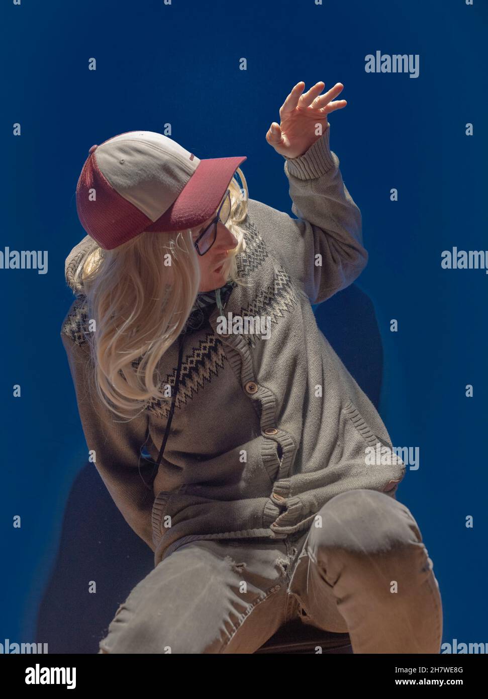 Blonde lange Haare Mann mit roter Mütze und grauen Hosen und heißen ...