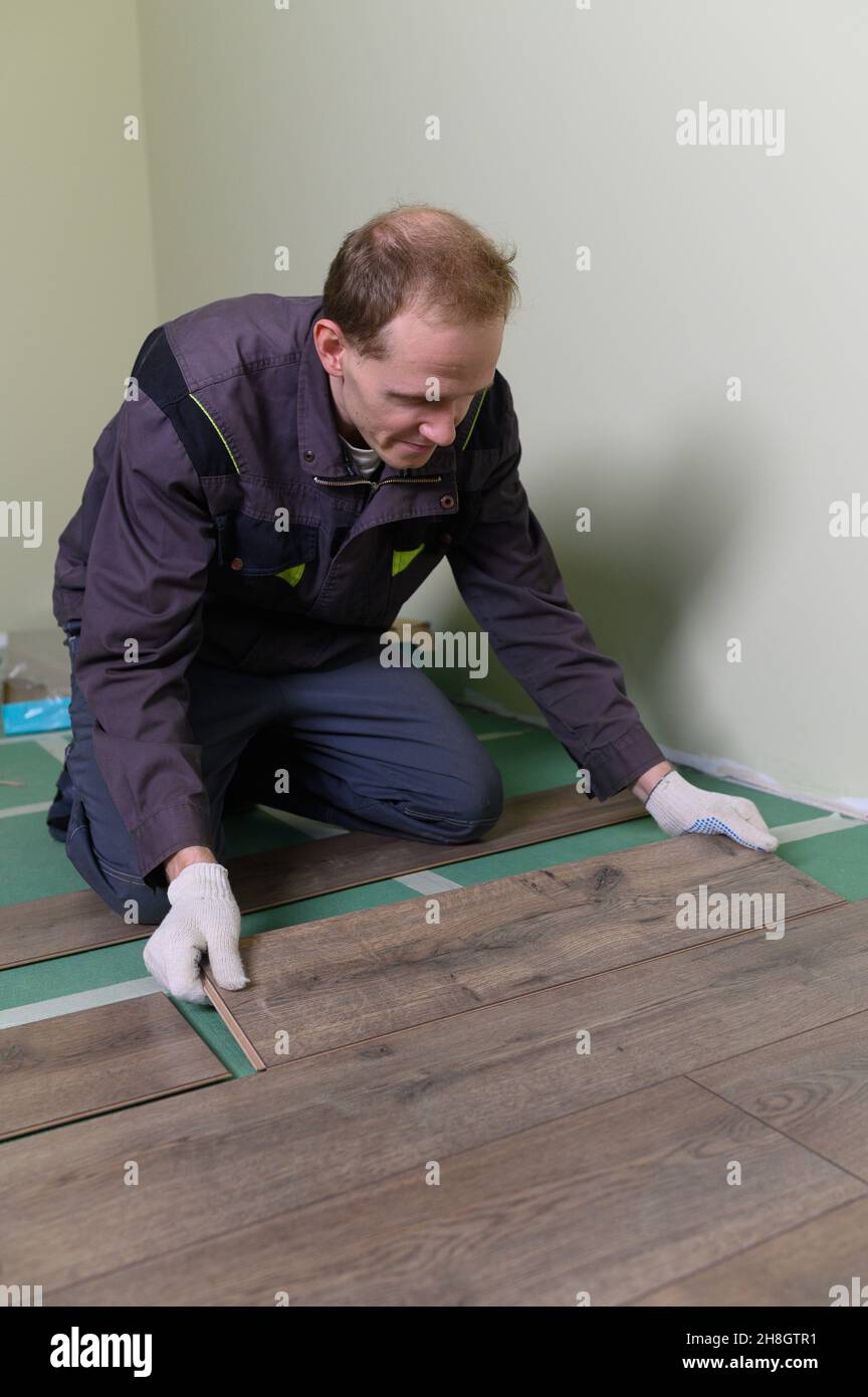 Der Master legt das Laminat ab. Der Mann repariert den Boden ...