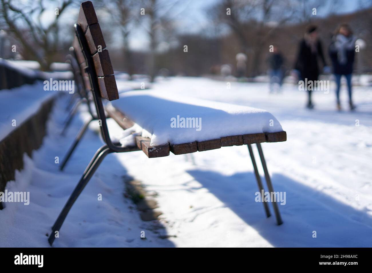 Teil einer Bank mit Schnee im Park zwei Frauen sprechen miteinander ...