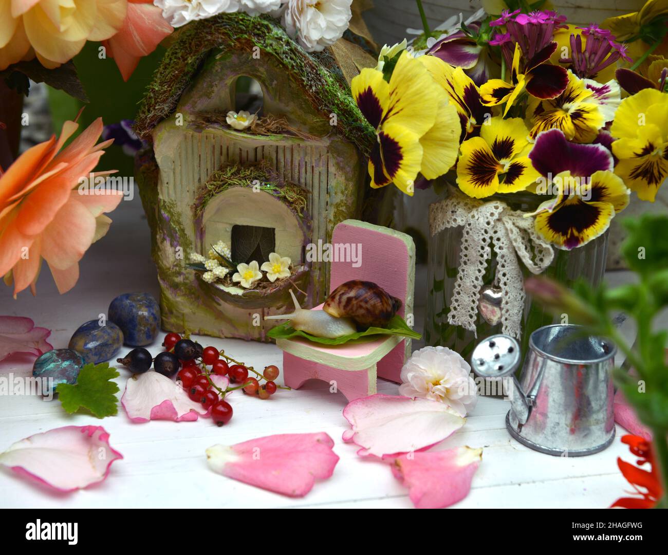 Schönes Miniaturhaus oder Cottage und kleine Schnecke zwischen Blumen ...