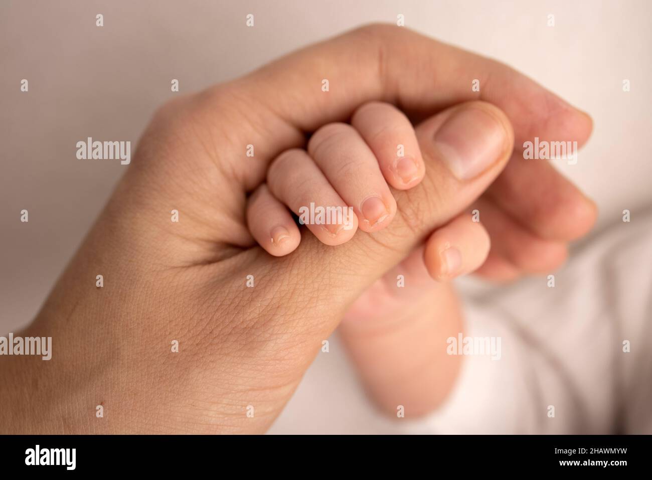 Das neugeborene Baby in einem weißen Schließen hat einen festen Griff ...