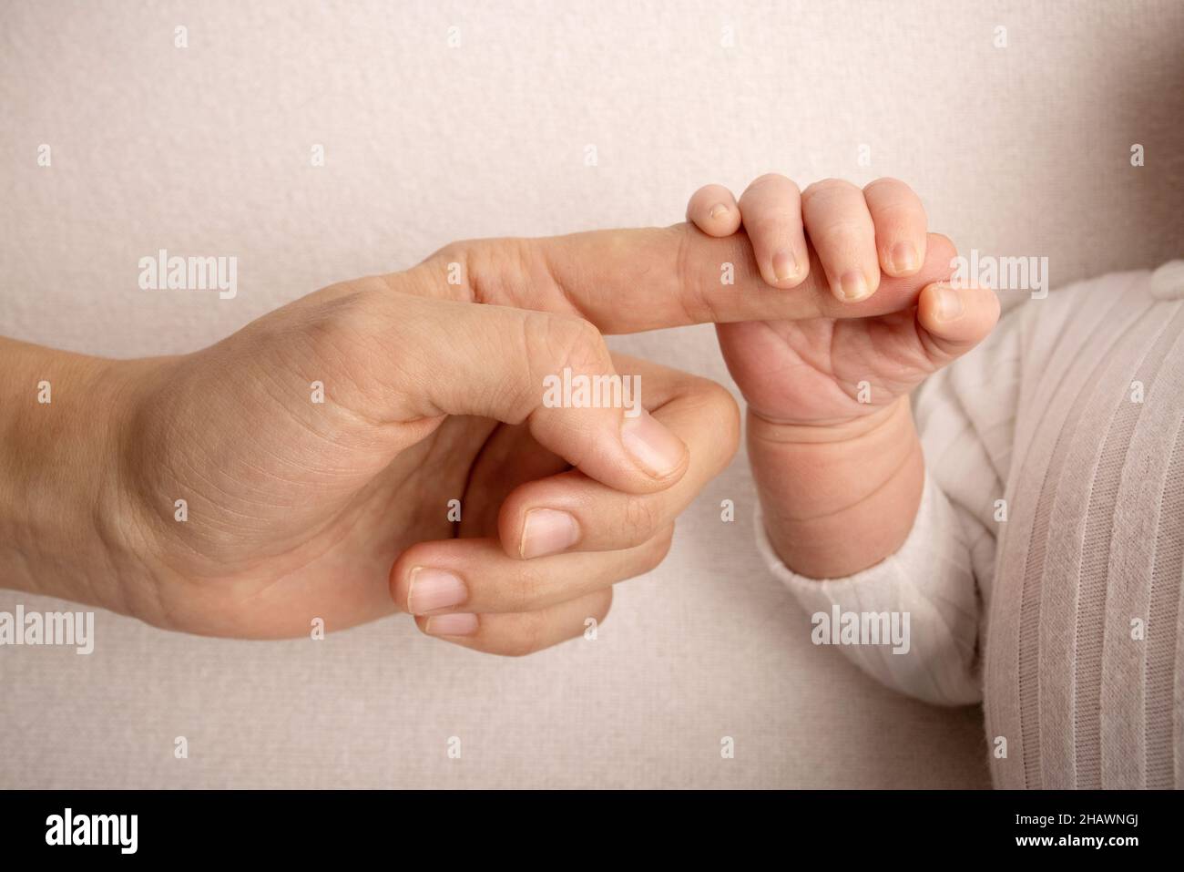 Das neugeborene Baby in einem weißen Schließen hat einen festen Griff ...