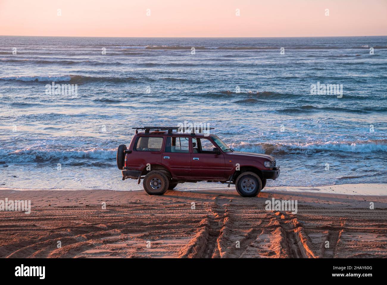 Rotes Offroad-Auto, das am Strand am Strand am Strand am Strand geparkt ...