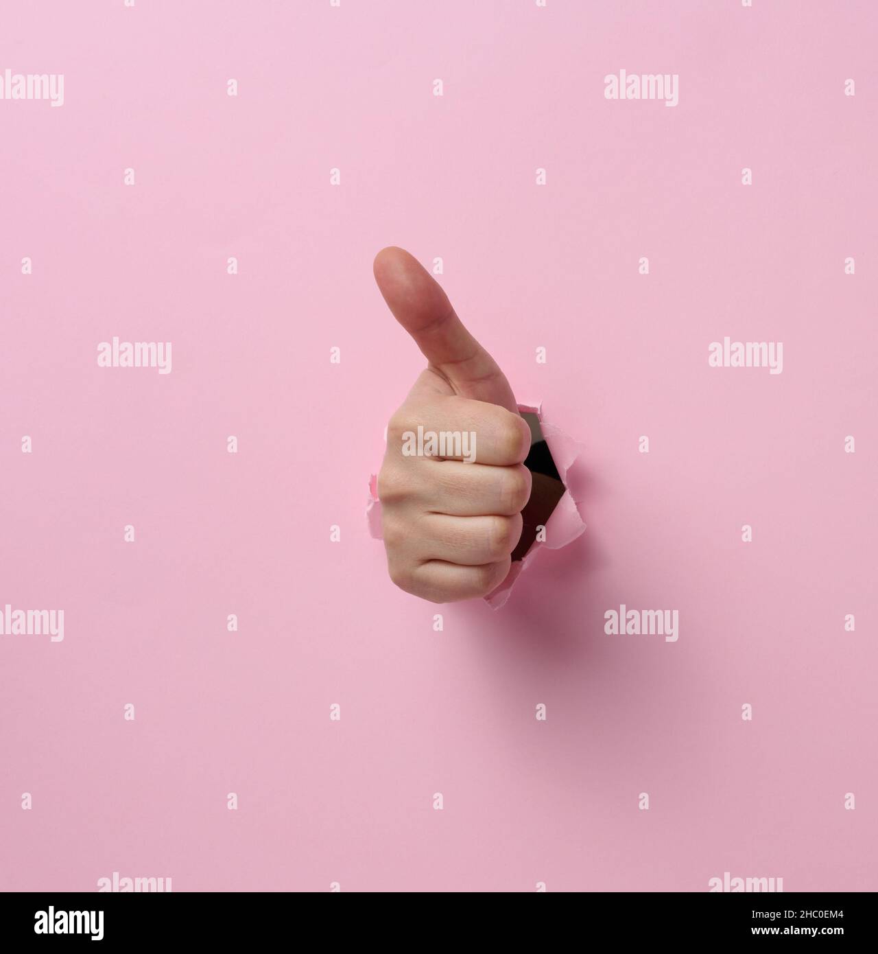 Die Hand einer Frau ragt aus dem zerrissenen Loch und zeigt eine Geste ...