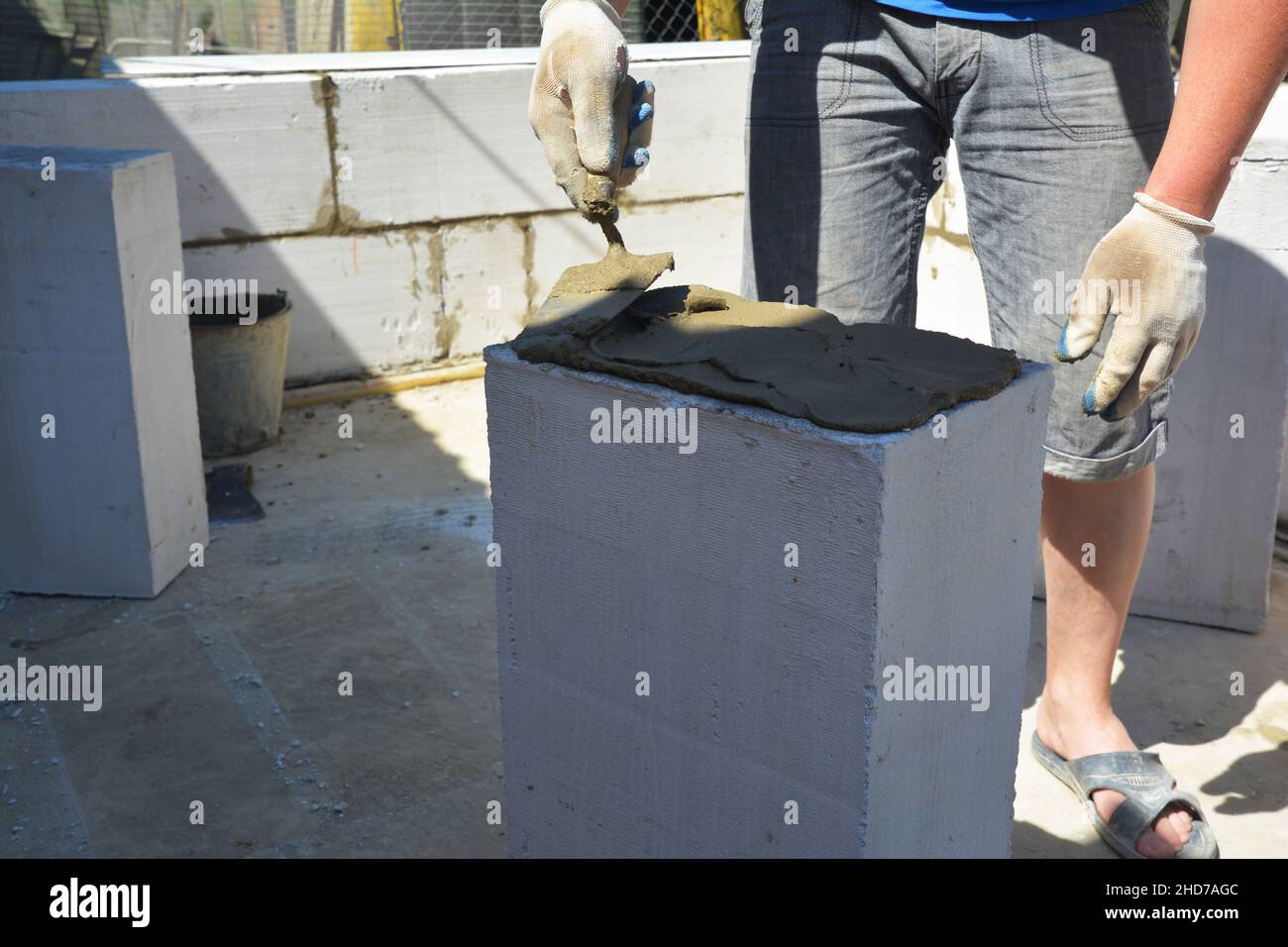 Bau einer Betonblockwand. Der Auftragnehmer verlegt Betonblöcke und ...