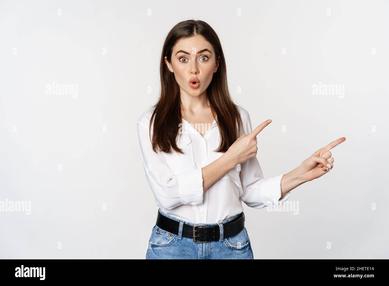 Verblüffte junge Frau, die mit den Fingern nach unten zeigt, Ansage ...