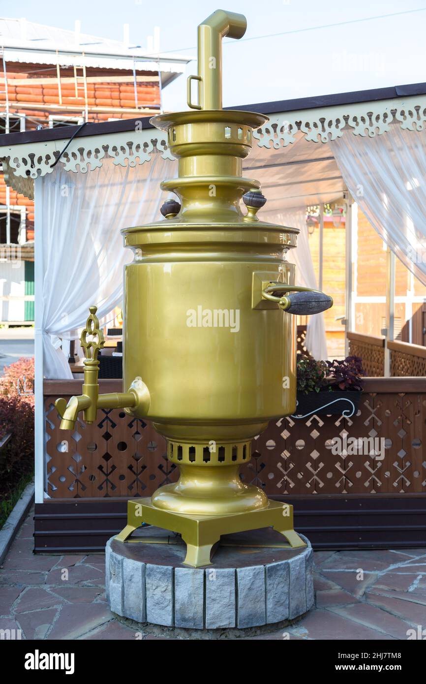 Ein großer goldener Samowar aus Metall auf der Straße der Stadt, eine ...