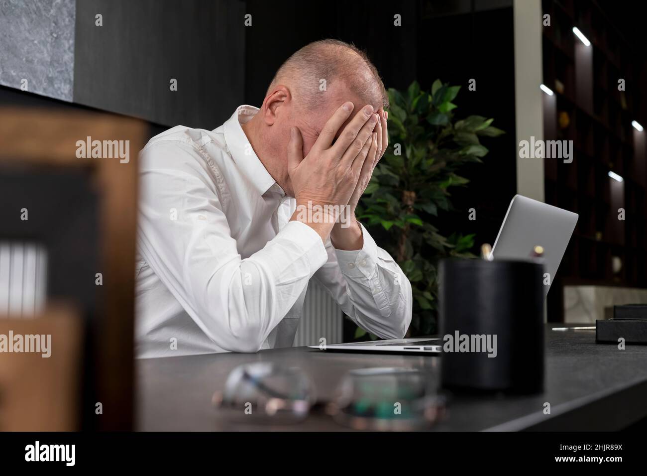 Verärgert und frustriert Geschäftsmann sitzt am Bürotisch mit Laptop ...