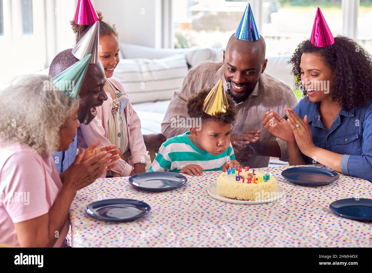 Familie mit mehreren Generationen, die zu Hause um den Tisch sitzt und den Geburtstag des Jungen ...