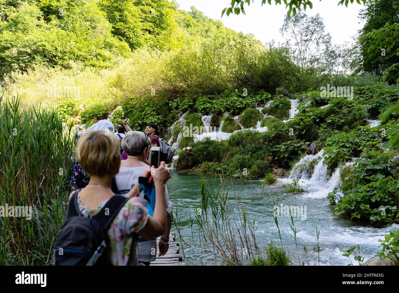 Gruppe von Touristen, die Fotos von einem Wasserfall in den unteren Plitvicer Seen, Kroatien ...