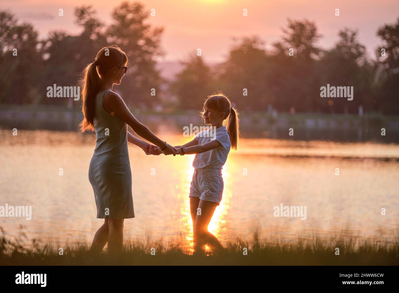 Glückliche Mutter und Tochter stehen zusammen und halten sich die Hände und genießen die Zeit im ...
