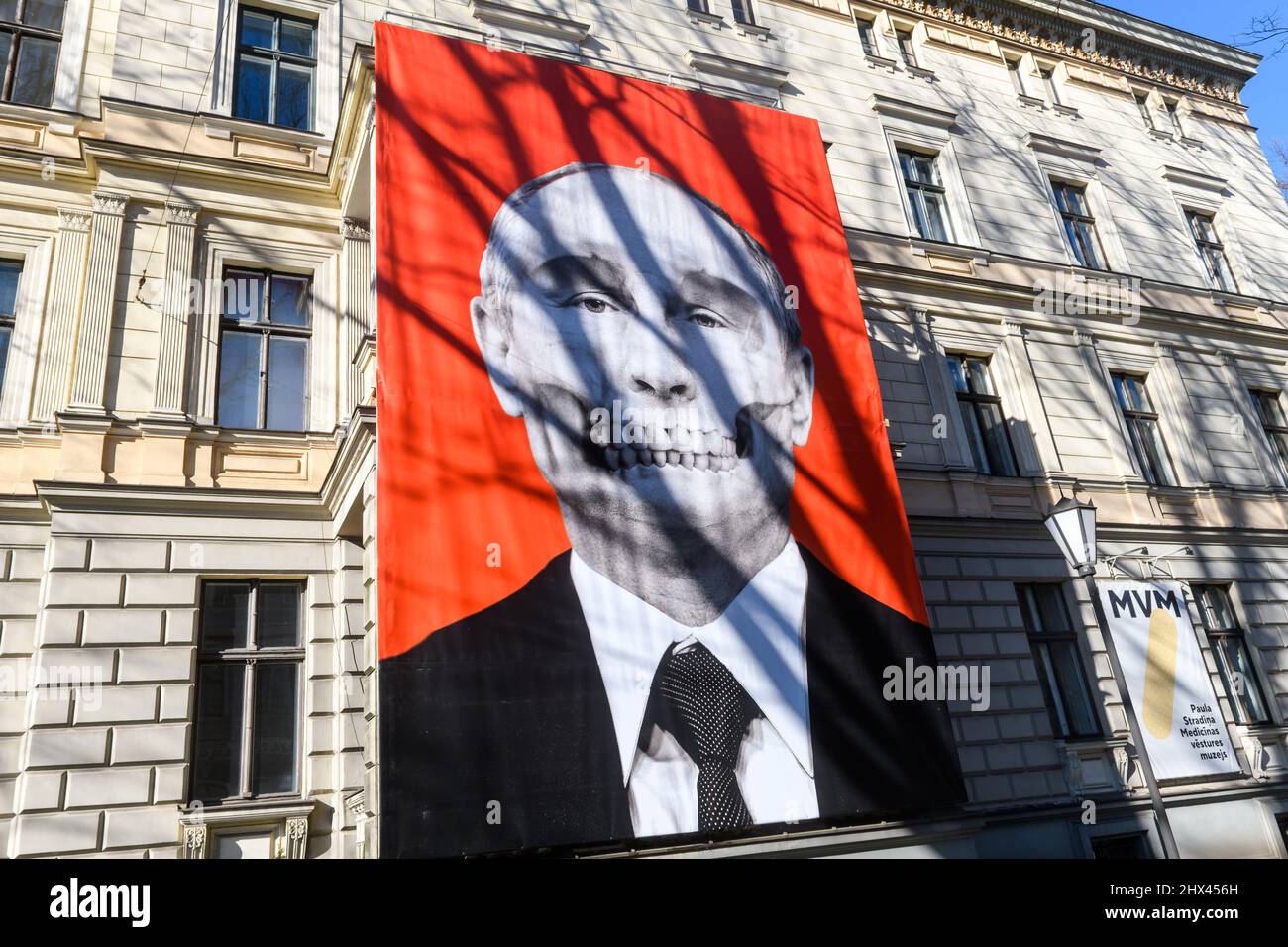 RIGA, LETTLAND. 9.. März 2022. Riesiges Banner mit Putins Schädel, das ... RIGA, LETTLAND. 9.. März 2022. Riesiges Banner mit Putins Schädel, das ...