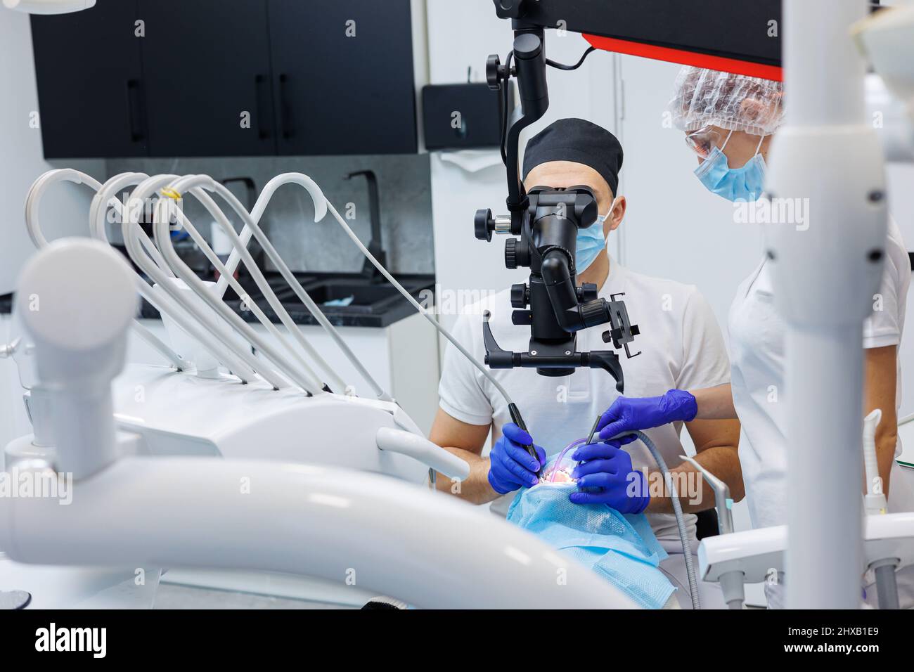 Ein erfolgreicher Zahnarzt schaut mit einem Zahnmikroskop auf die Zähne ...