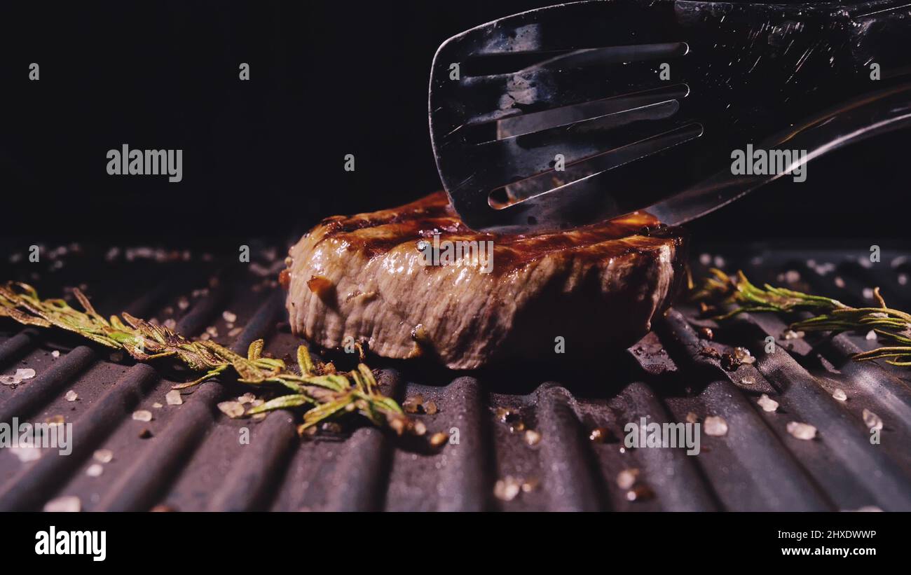 Köstliche saftige Fleisch Steak Kochen auf dem Grill. Küchenzange ...
