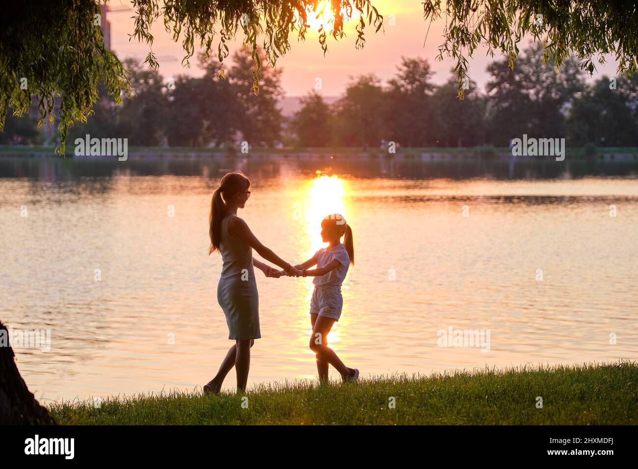 Glückliche Mutter und Tochter stehen zusammen und halten sich die Hände und genießen die Zeit im ...