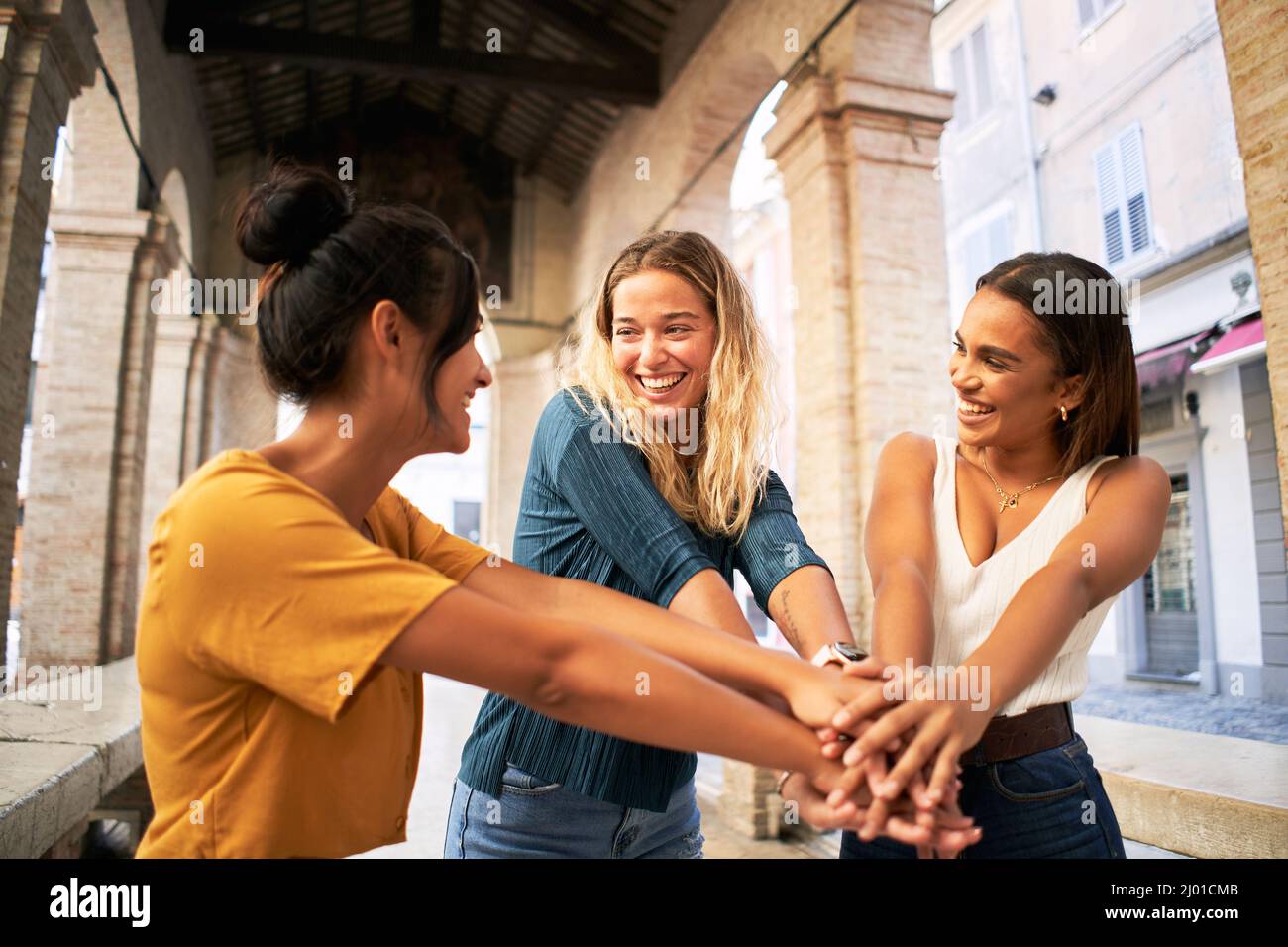 Glückliche junge Freundinnen stapeln die Hände. Eine vielfältige Gruppe ...