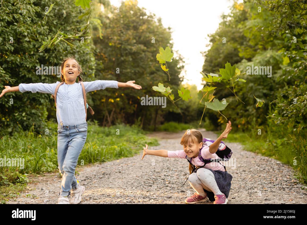Zwei Mädchen gehen im Sommer im Park, reden, gehen nach Schule und College, halten sich die ...