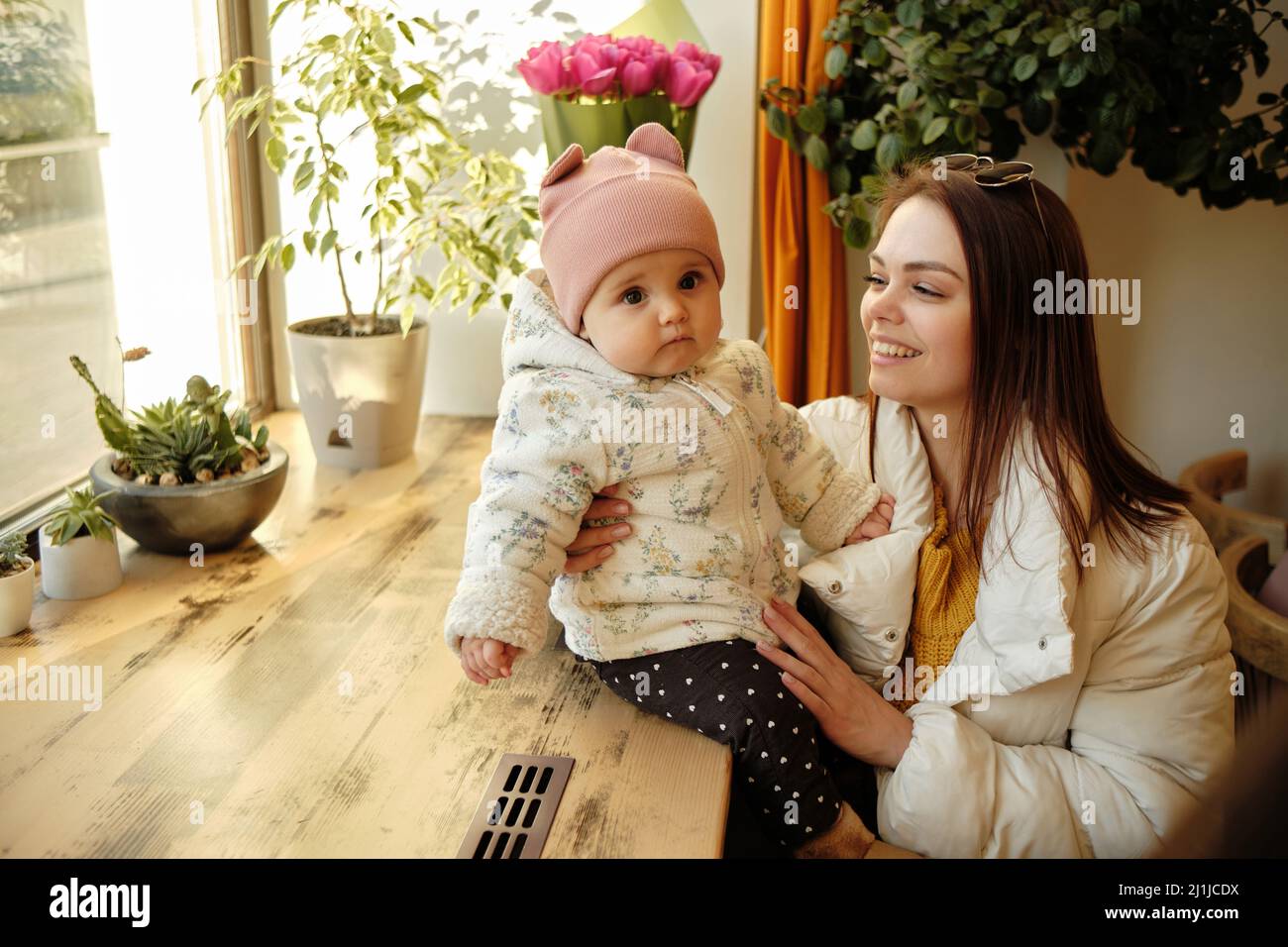 Junge und hübsche Mutter im Cafe sitzen mit ihrer kleinen Tochter ...